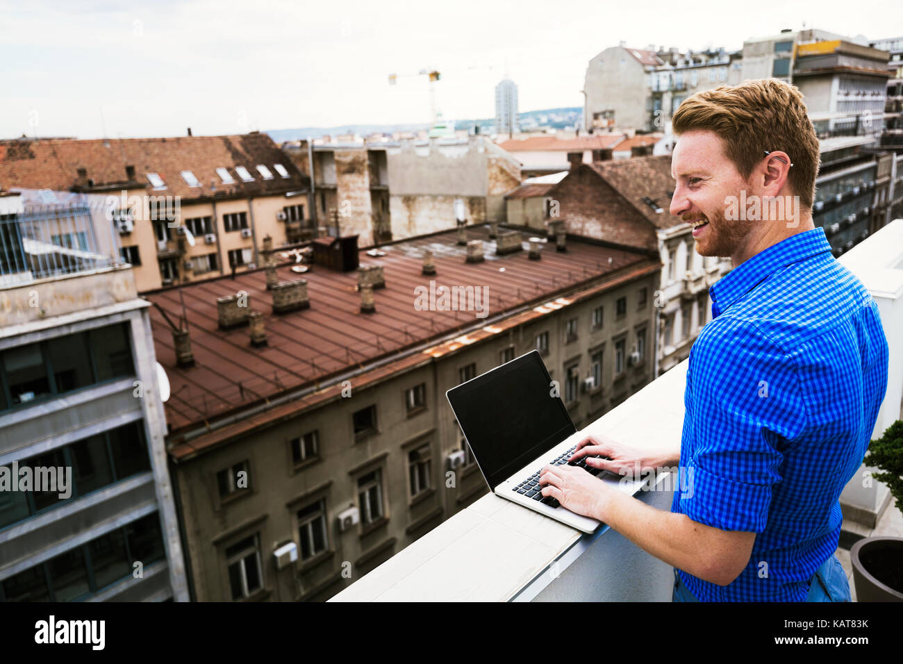 Business person using laptop on rooftop Stock Photo - Alamy