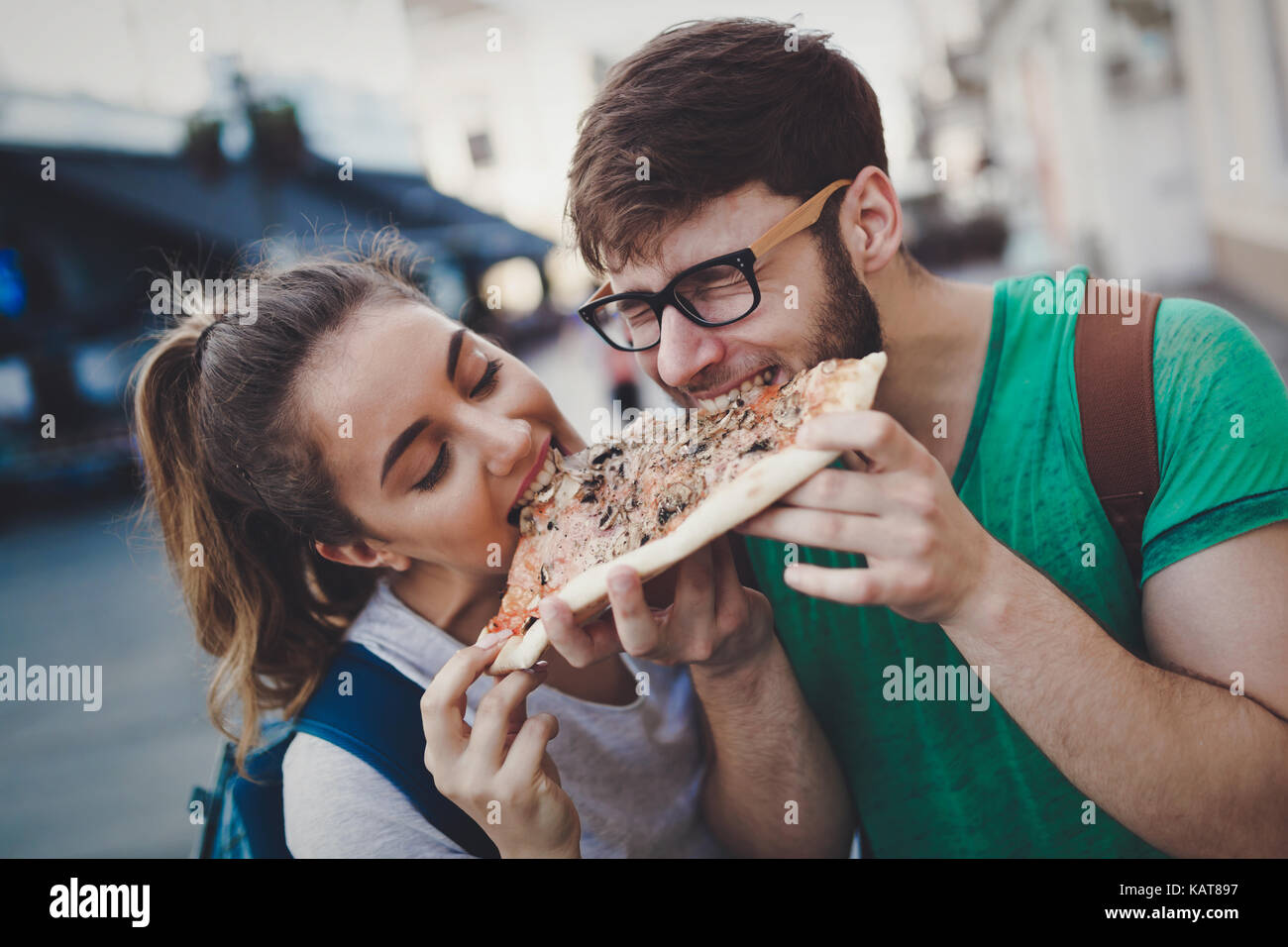 Happy couple sharing pizza on street Stock Photo - Alamy