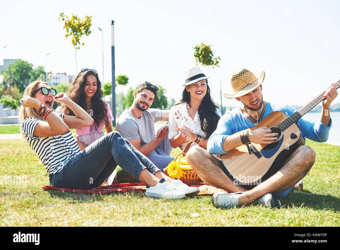 Happy young friends having picnic in the park.They are all happy,having ...