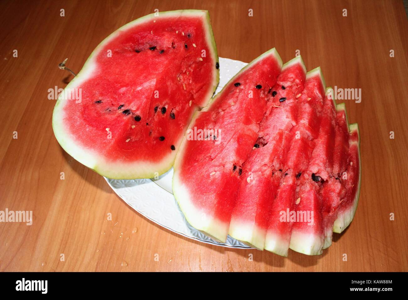 A ripe watermelon is cut and lies on a large white dish Stock Photo - Alamy