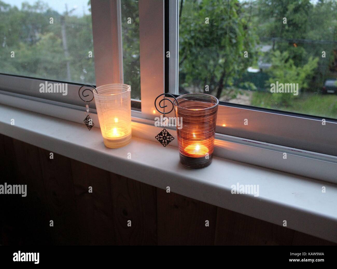 Two candles burning on the windowsill in deep candle holders Stock ...