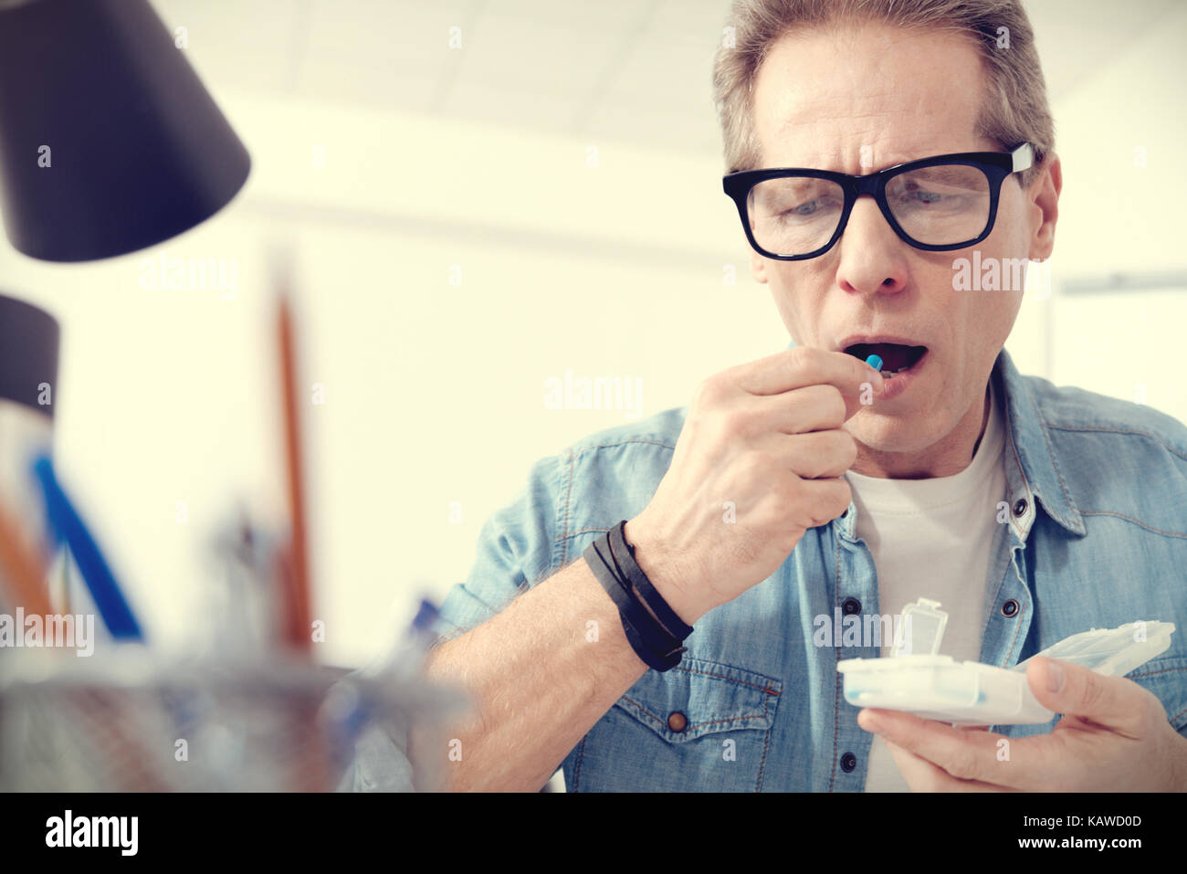 Nice pleasant man taking a pill Stock Photo - Alamy