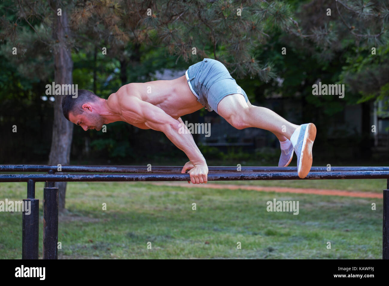 Young muscular young man doing exercises on the parallel bars in the ...