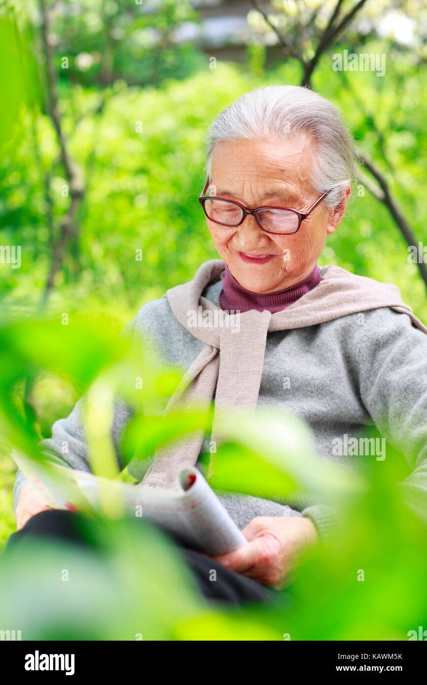 One happy Senior Chinese woman reading book in the yard Stock Photo - Alamy