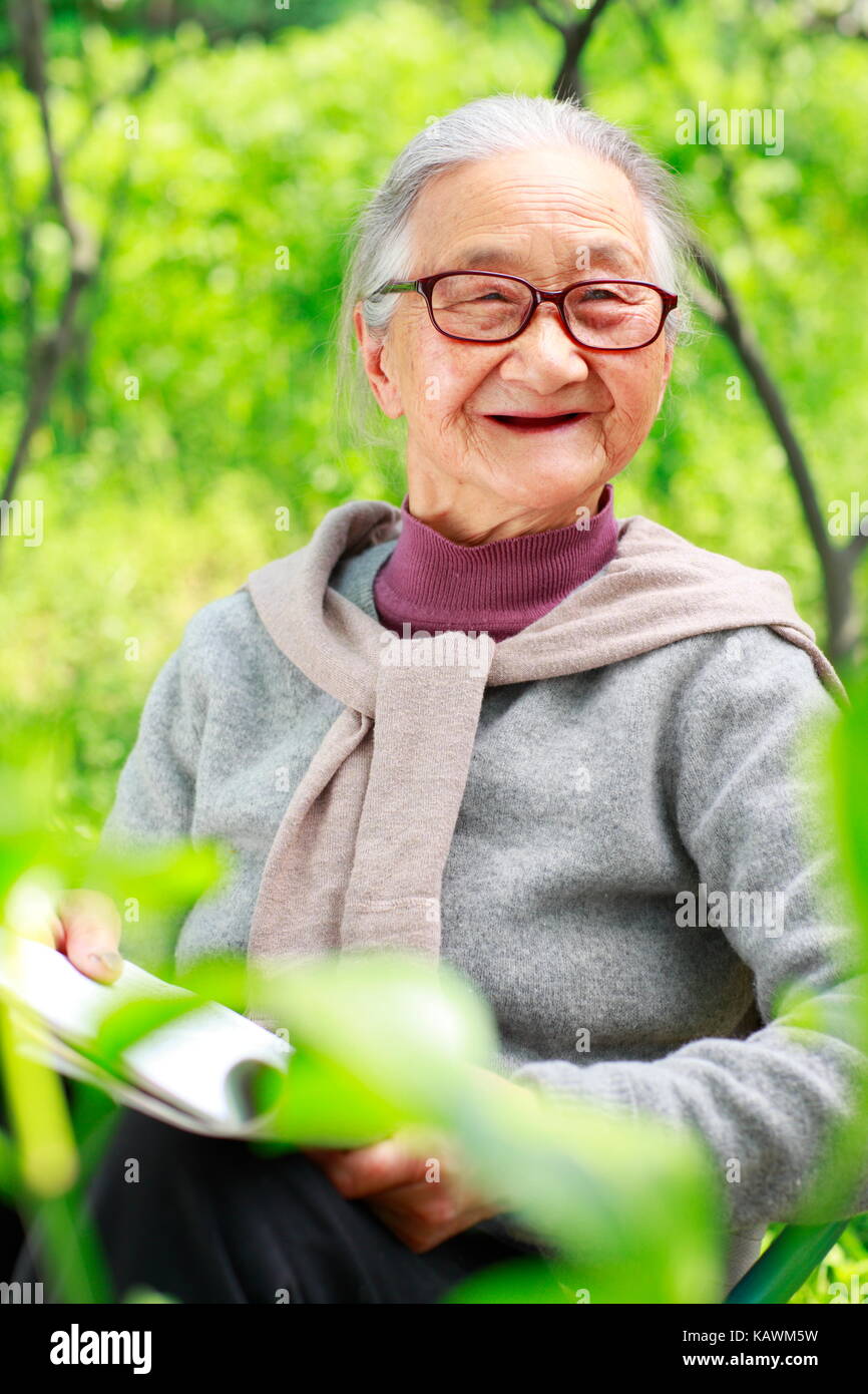 One happy Senior Chinese woman reading book in the yard Stock Photo - Alamy