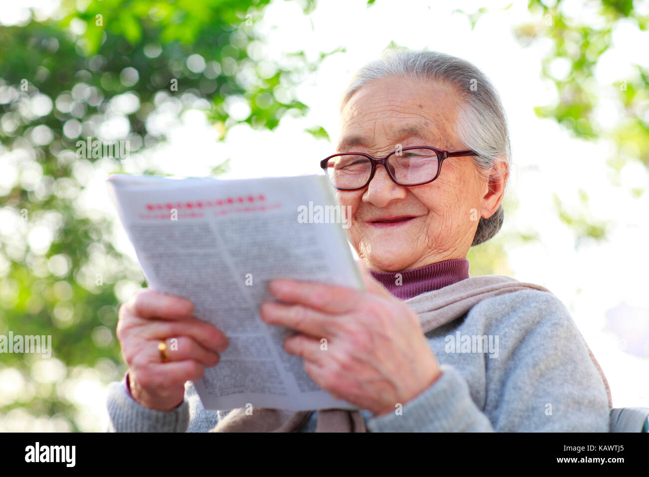 One happy Senior Chinese woman reading book in the yard Stock Photo - Alamy