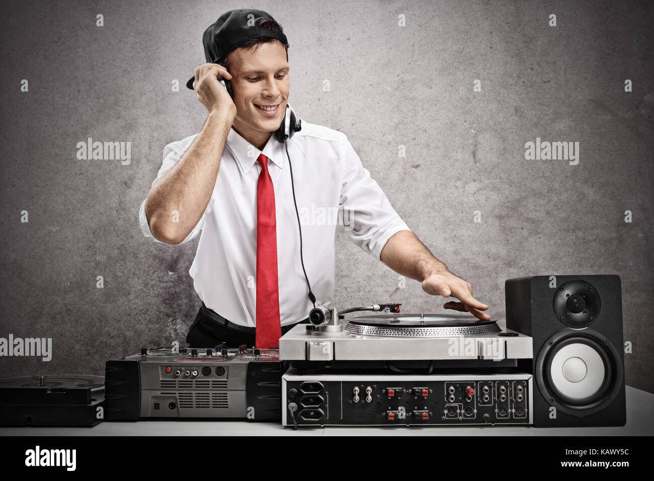 Formally dressed man playing music on a turntable against a rusty gray ...