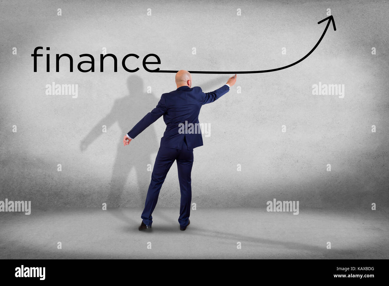 View of a Businessman in front of a wall writing the word finance with ...