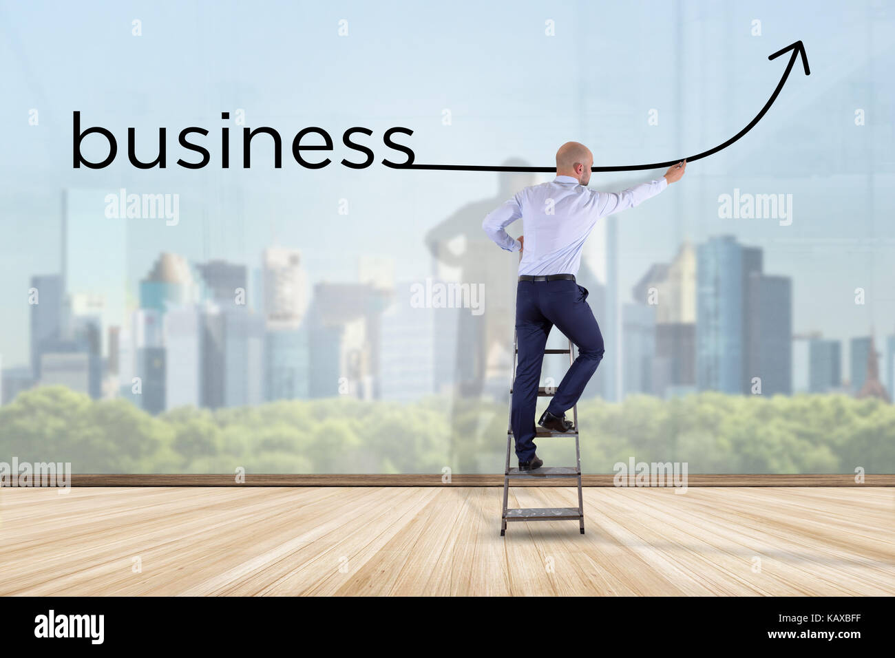 View of a Businessman in front of a wall writing the word business with ...