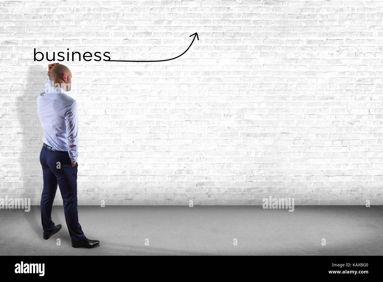 View of a Businessman in front of a wall thinking about the word ...