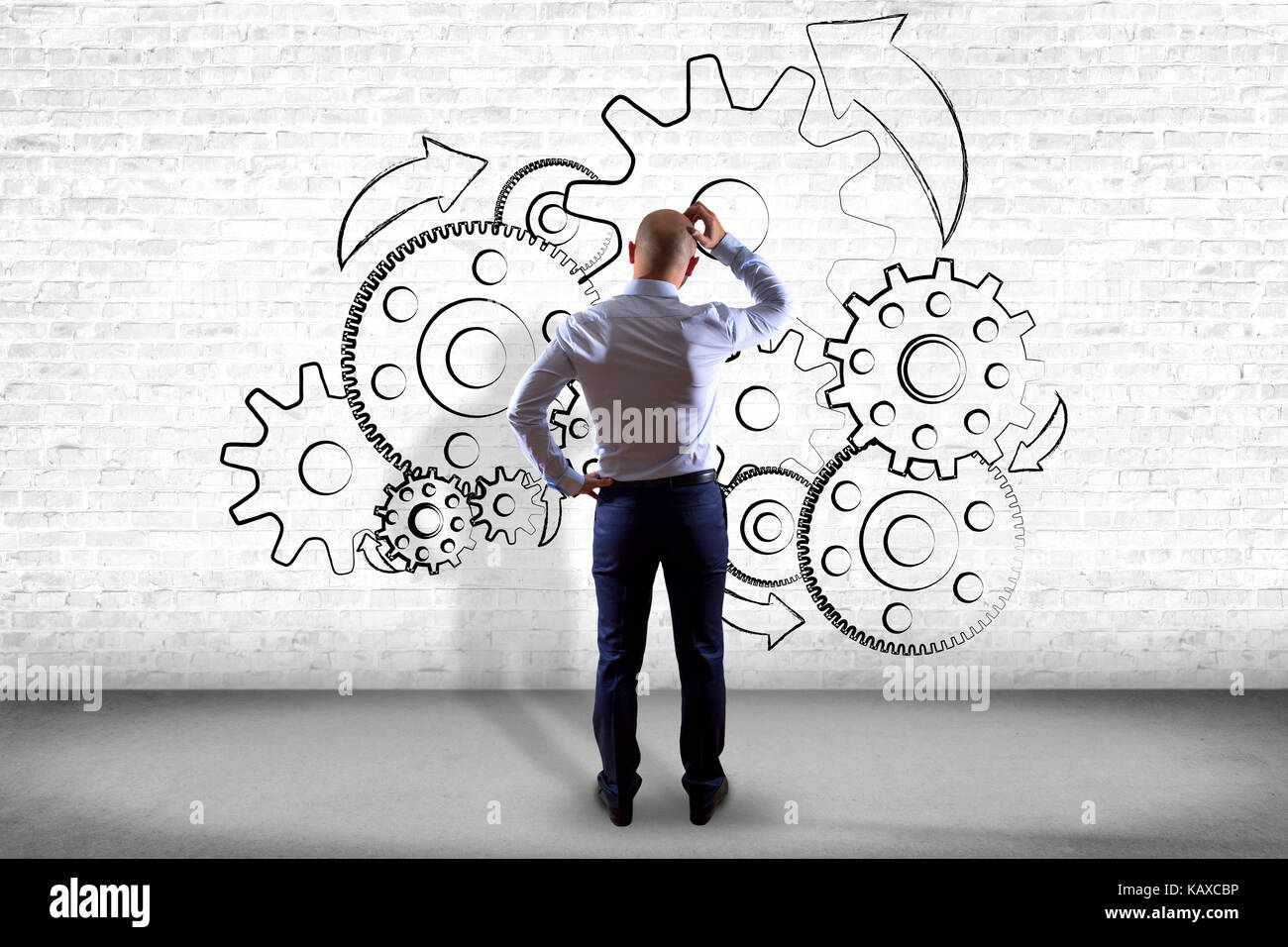 View of a Businessman in front of a wall thinking about a cog wheel ...