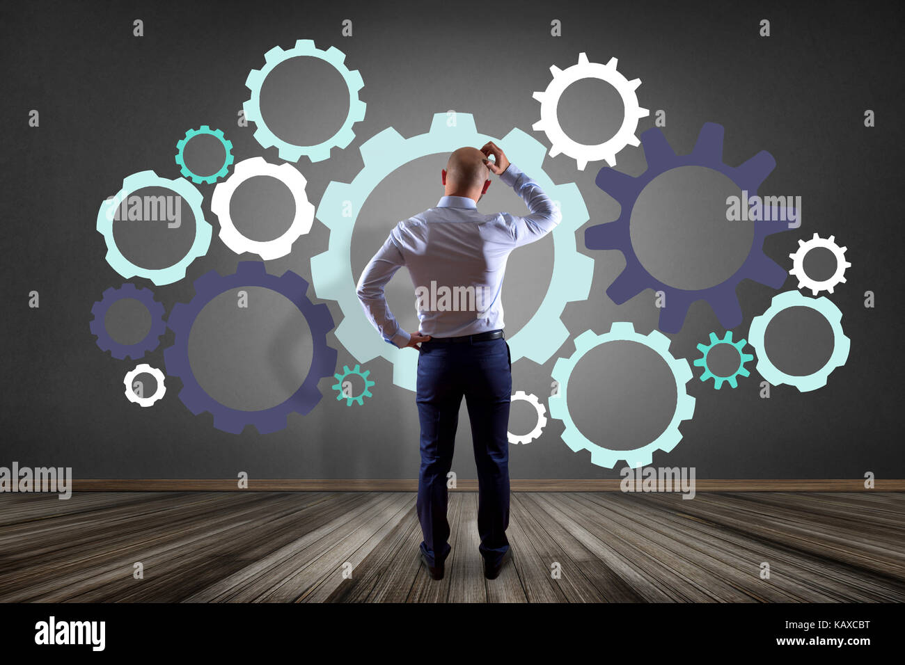 View of a Businessman in front of a wall thinking about a cog wheel ...