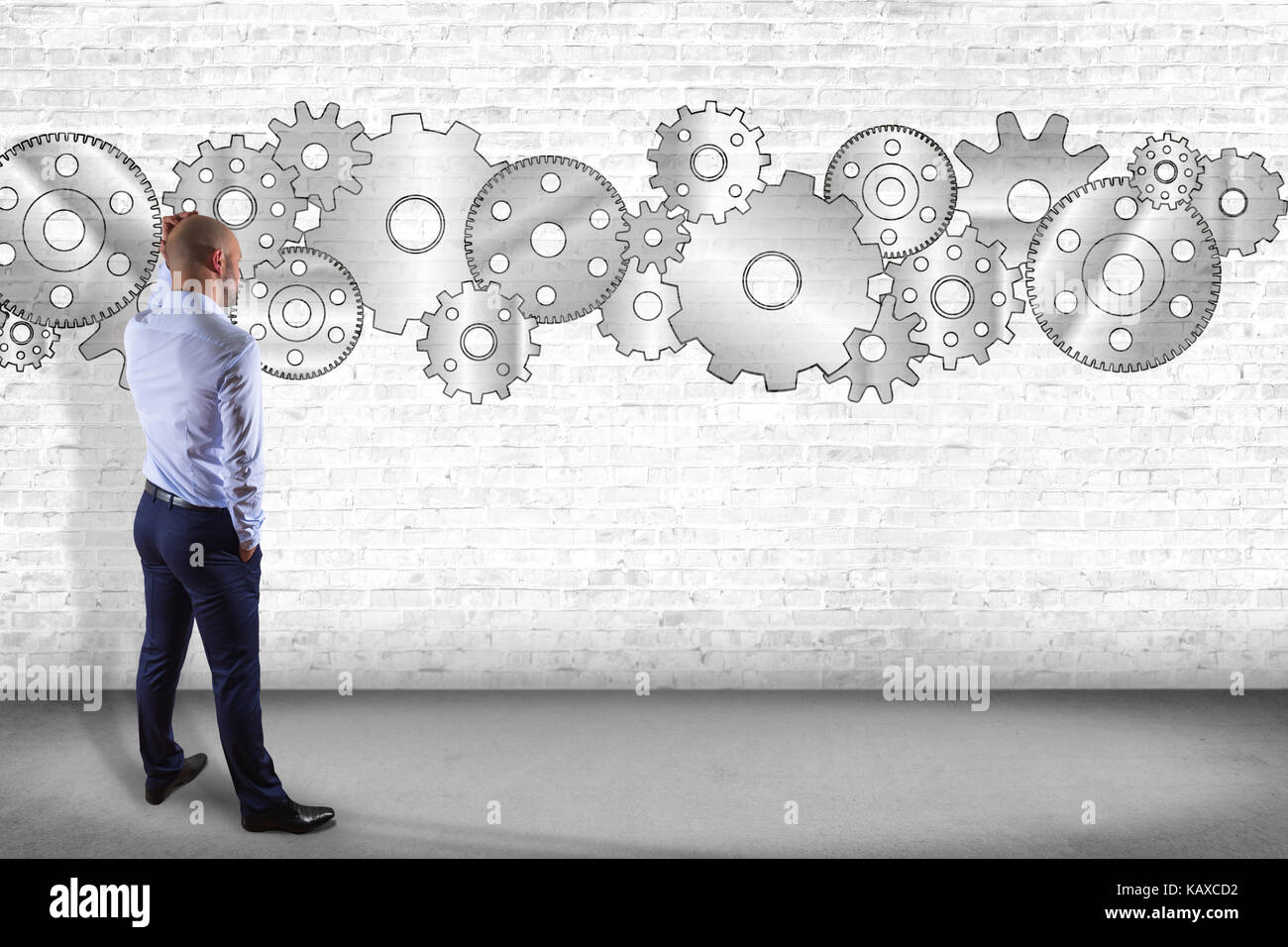 View of a Businessman in front of a wall thinking about a cog wheel ...