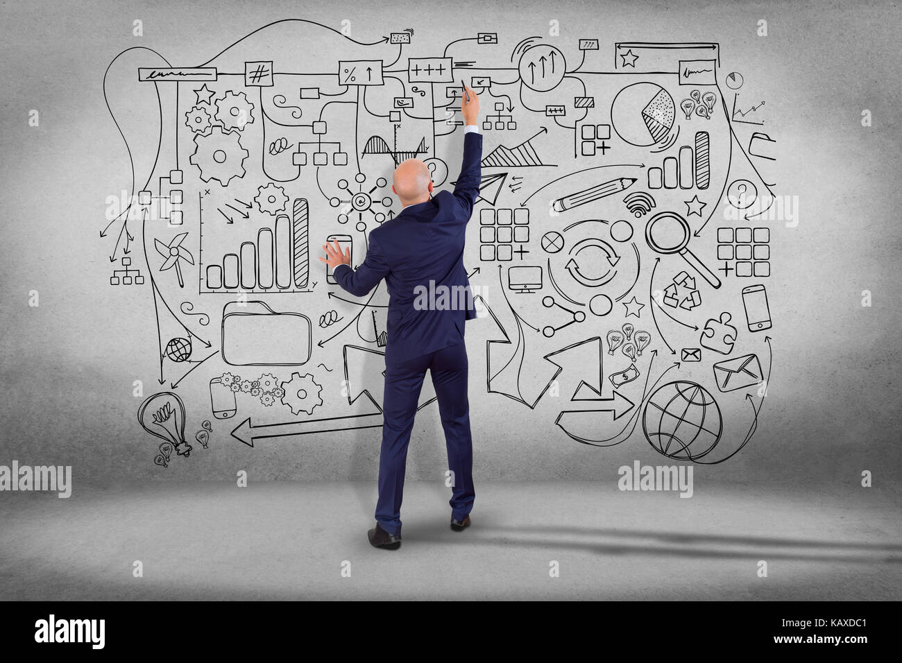 View of a Businessman drawing a hand drawn Complex schema on a wall ...