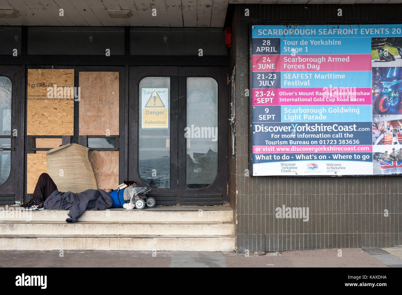 Homeless man sleeps at entrance to derelict cinema with entertainments ...