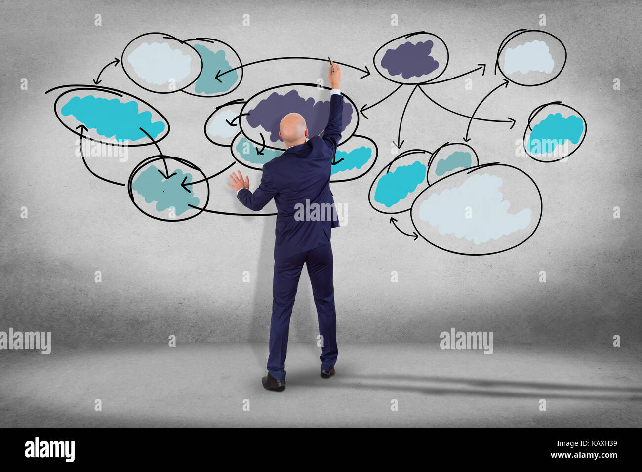 View of a Businessman in front of a wall writing on a business chart ...