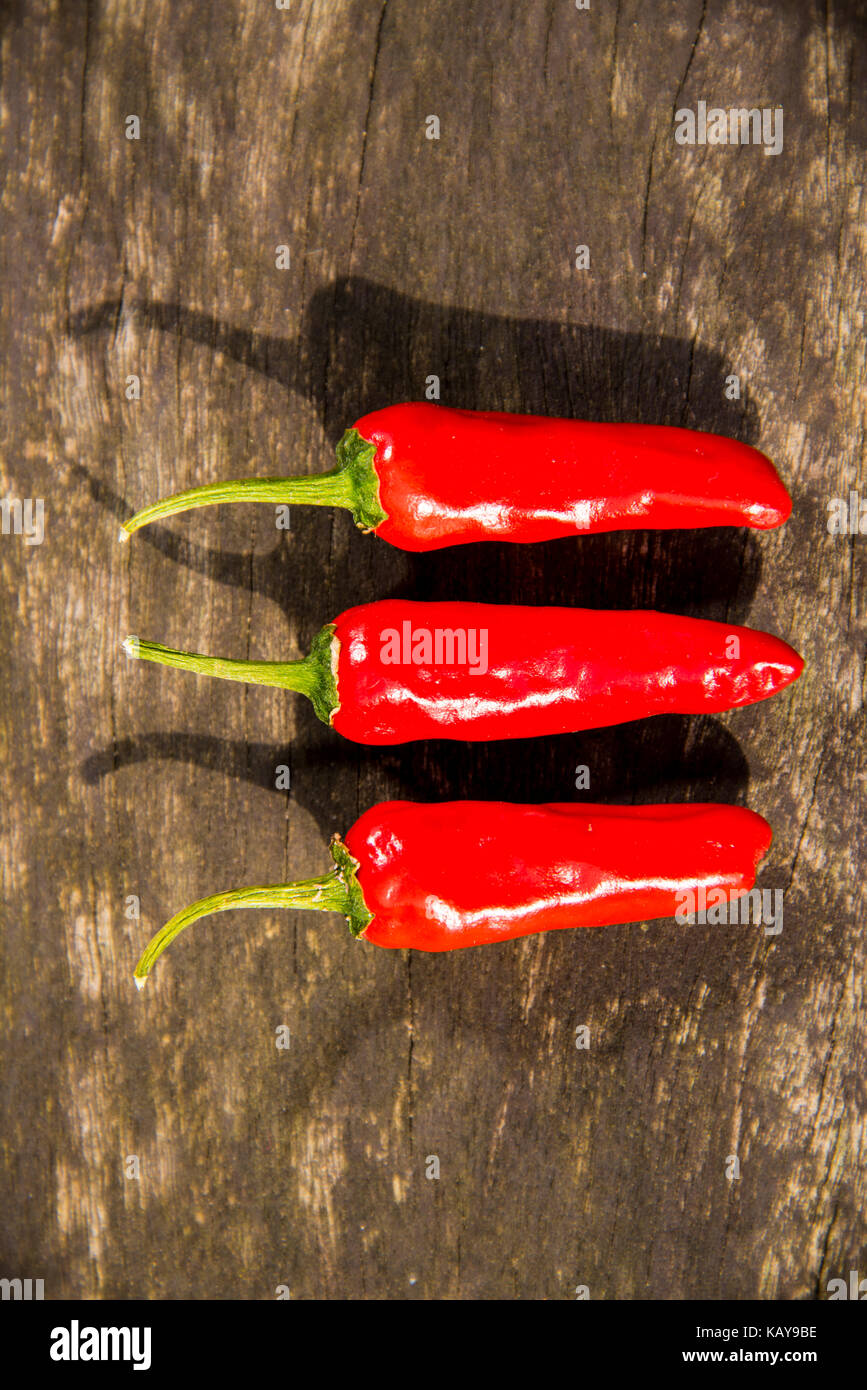 Three Red Chilli Peppers on a Wooden Background Stock Photo - Alamy