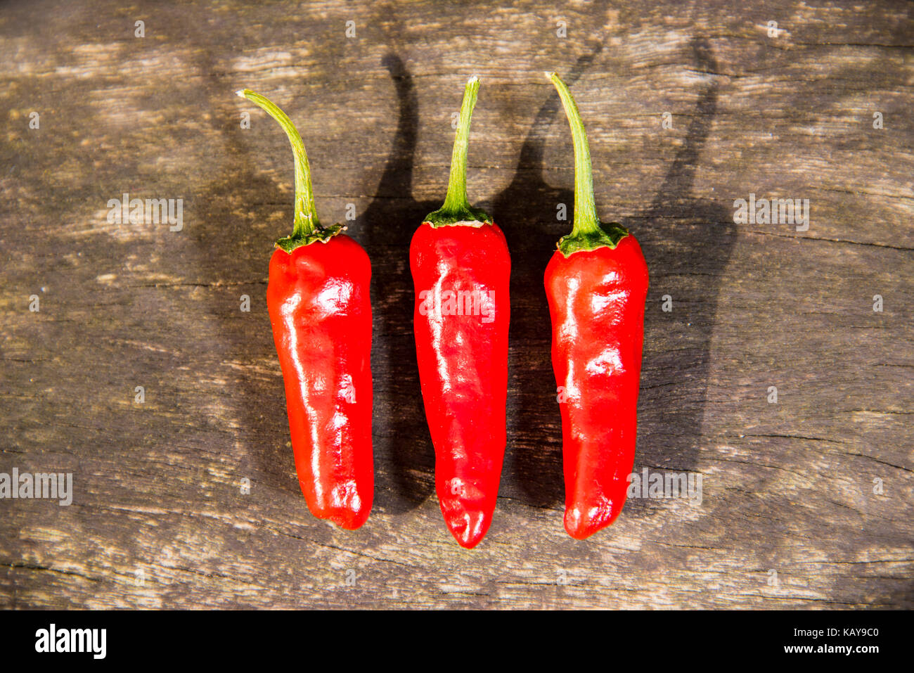 Three Red Chilli Peppers on a Wooden Background Stock Photo - Alamy