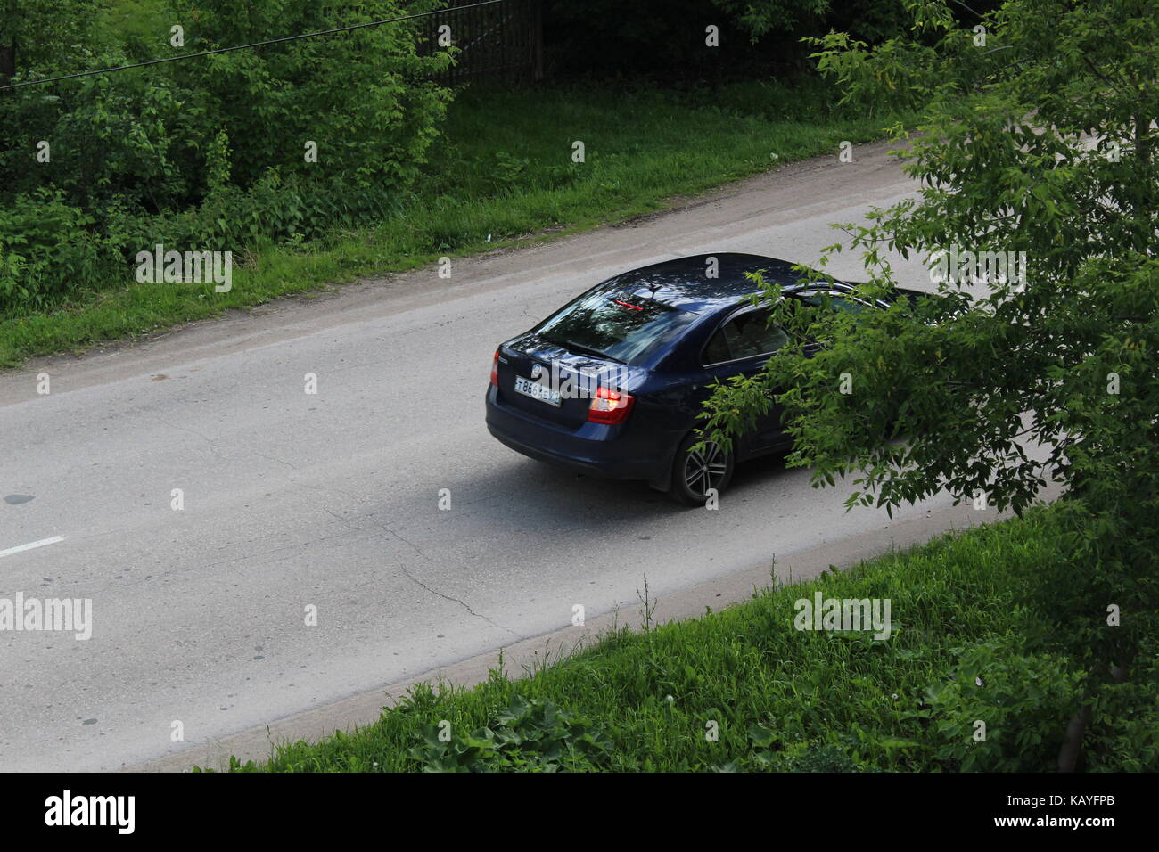 A car of dark blue color is moving along an asphalt road Stock Photo ...