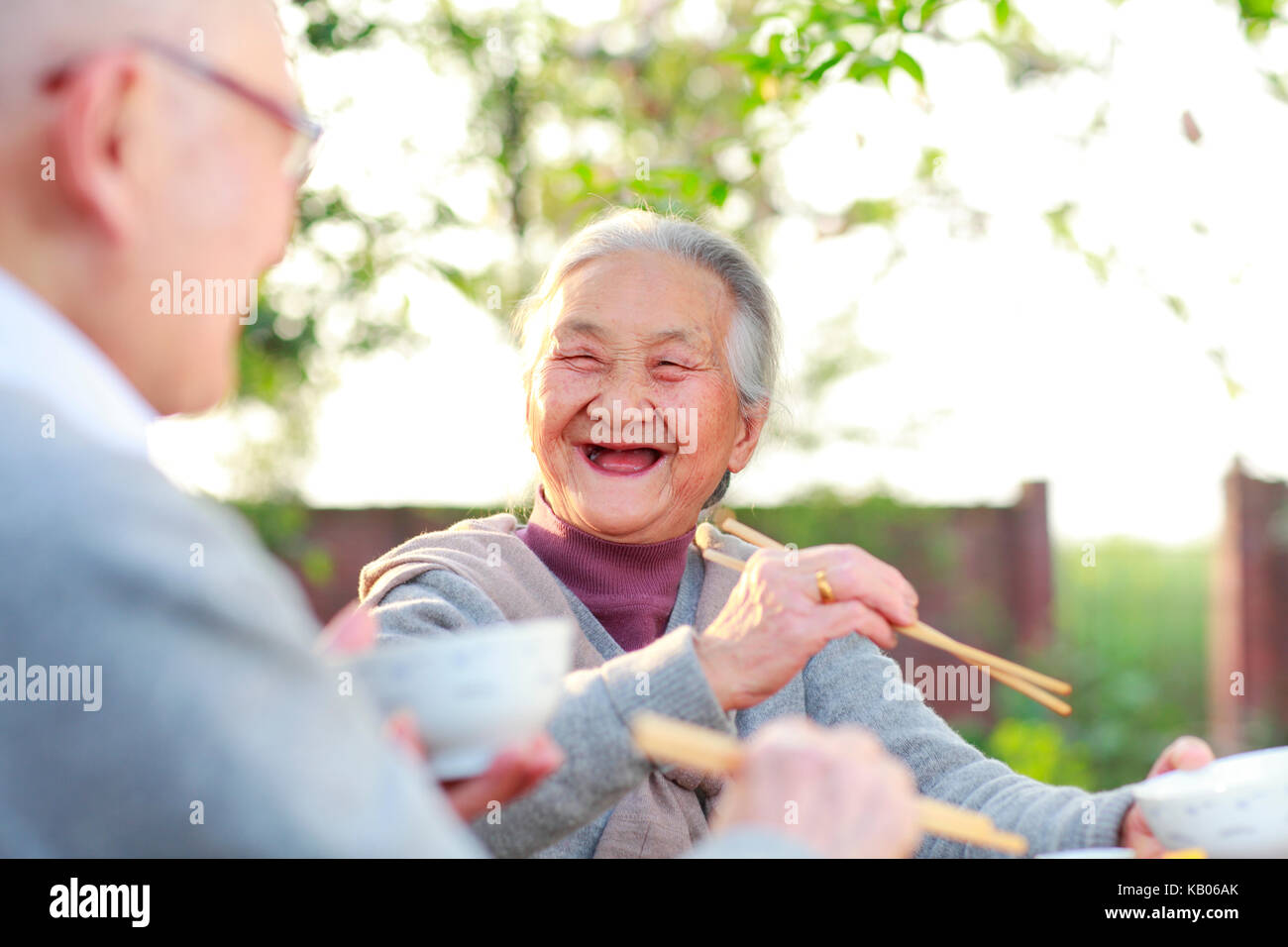happy and healthy Chinese senior couple together eating in the garden ...