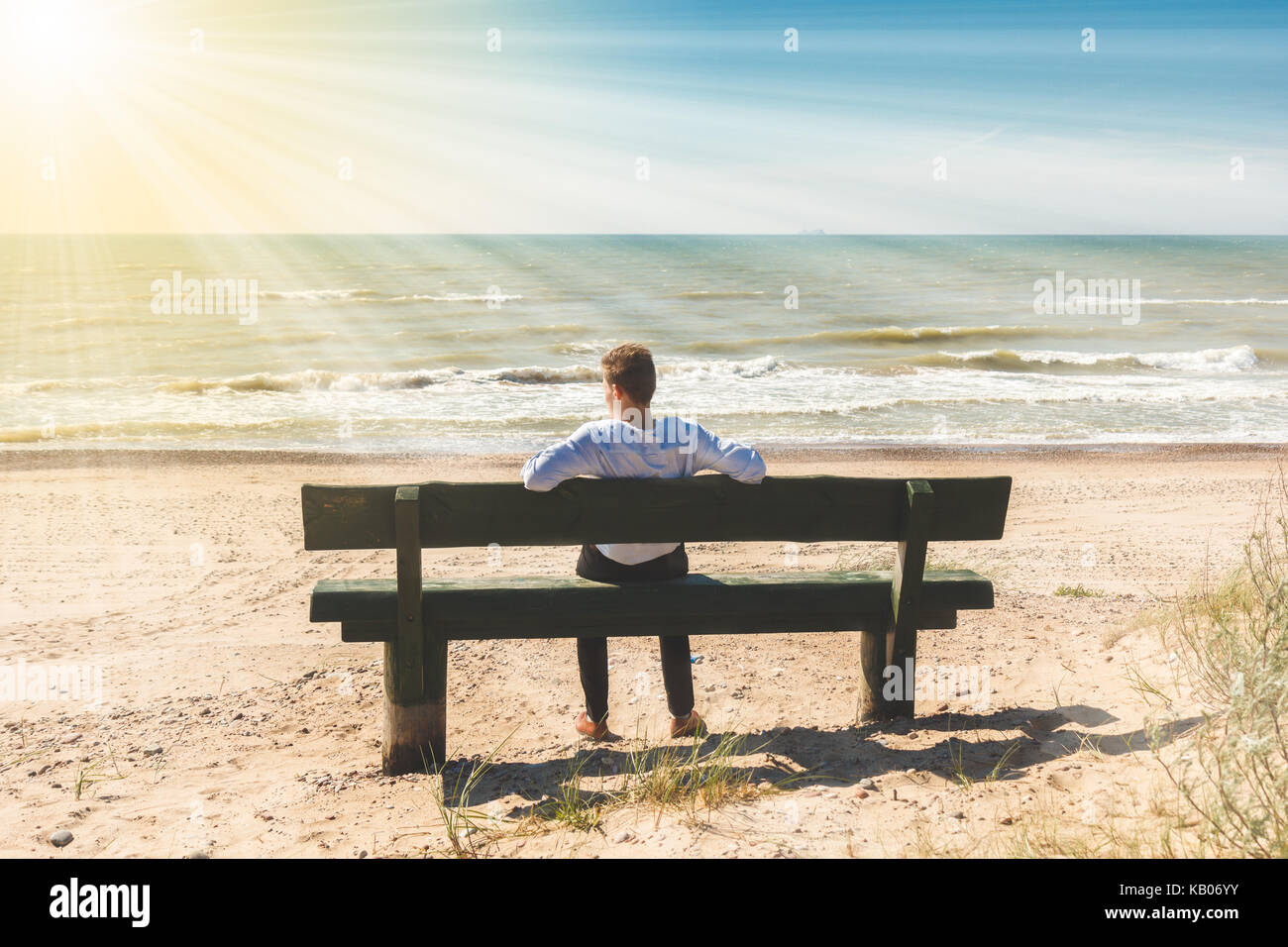 young man sitting on a lonely bench on the sea shore Stock Photo - Alamy