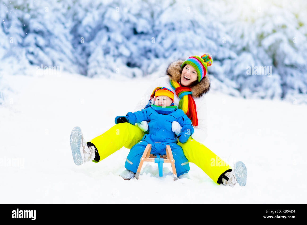 Mother and baby on sleigh ride. Child and mom sledding. Toddler kid ...