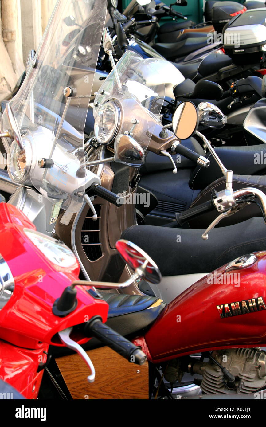 Crowded rows of motor scooters and motorcycles parked close together on ...