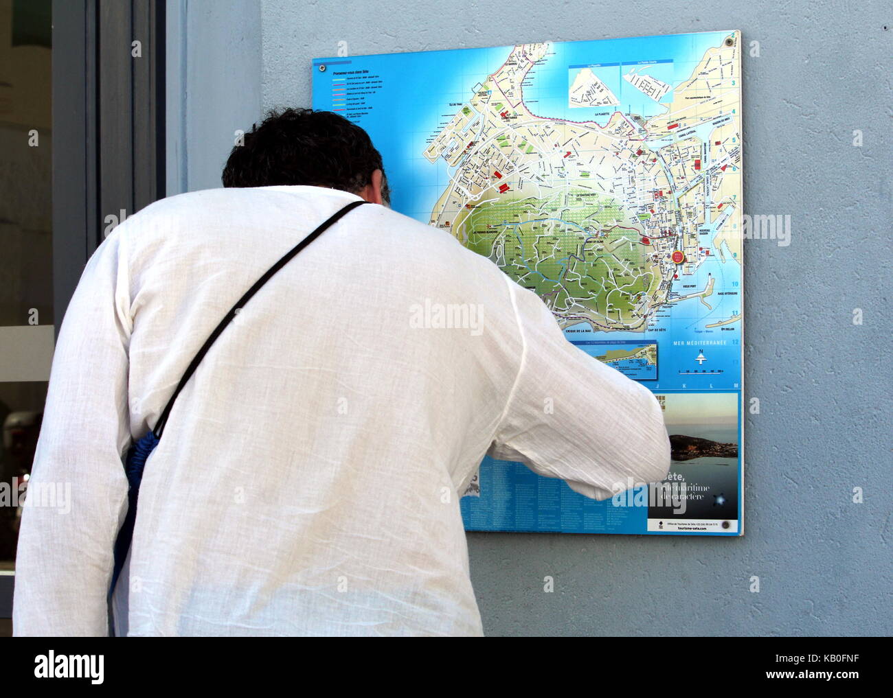 Man, a tourist, looking at a street map of Sete in Languedoc, France ...