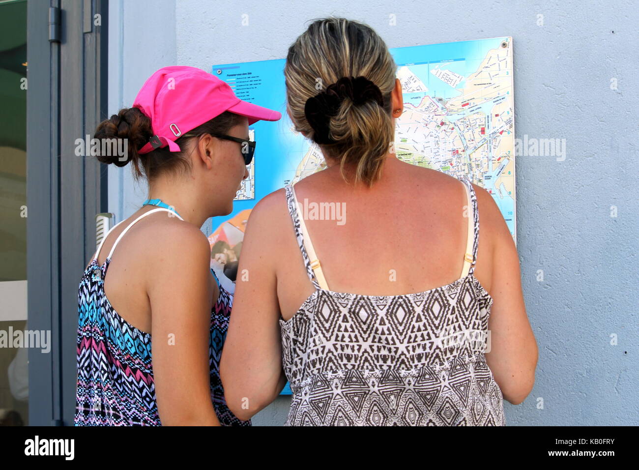 Woman and girl tourists looking at a street map of Sete in Languedoc ...