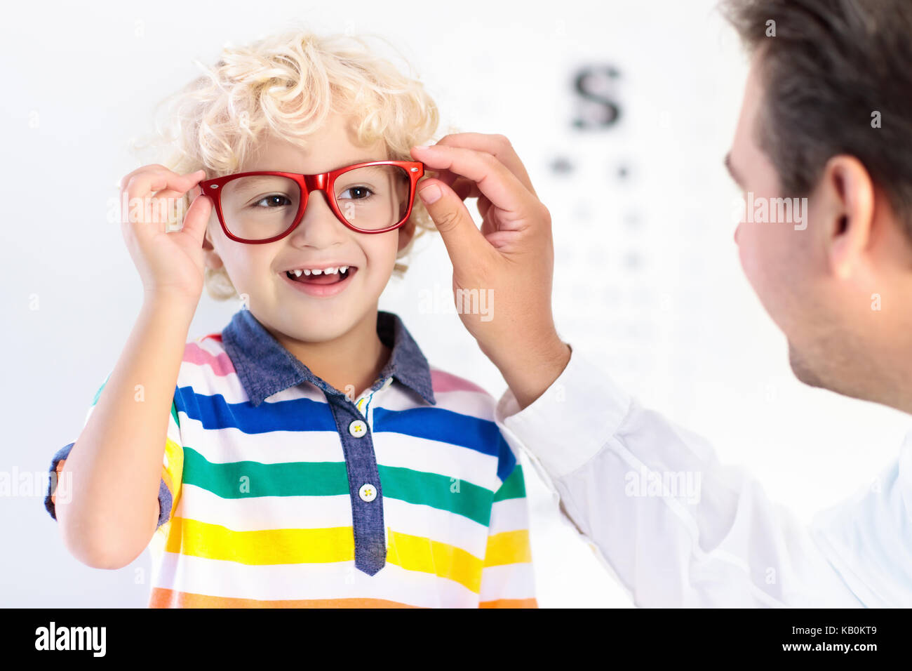 Child at eye sight test. Little kid selecting glasses at optician store ...