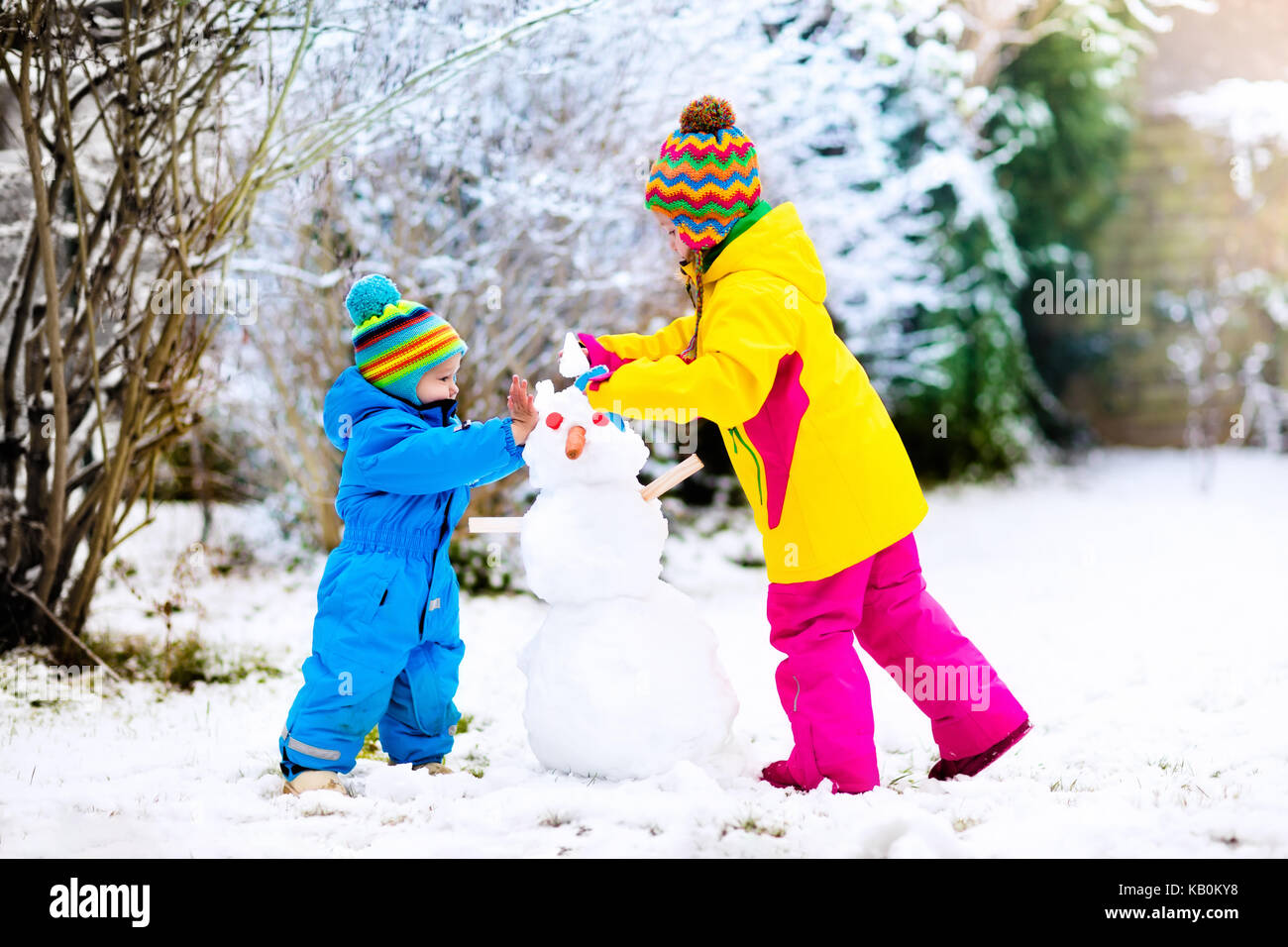 Children build snowman. Kids building snow man playing outdoors on ...