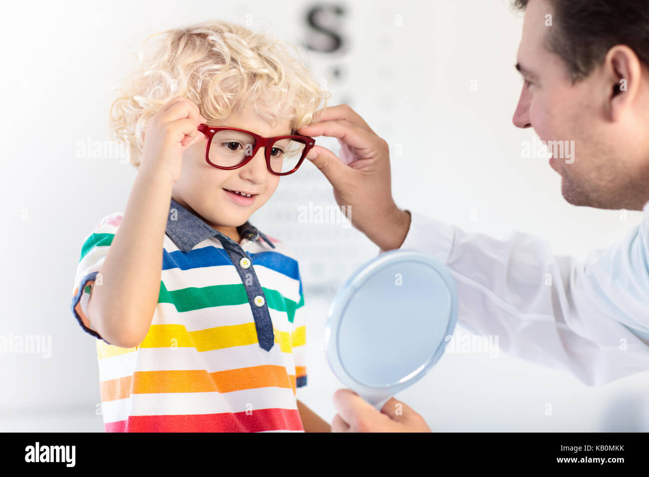 Child at eye sight test. Little kid selecting glasses at optician store ...