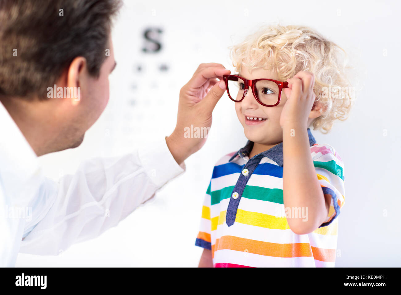 Child at eye sight test. Little kid selecting glasses at optician store ...