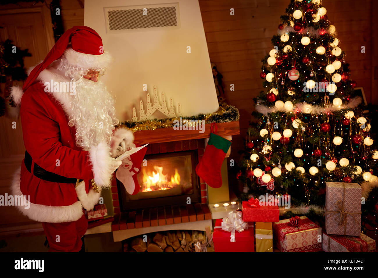 Santa Claus front Christmas and big stack of gift boxes checking wish ...
