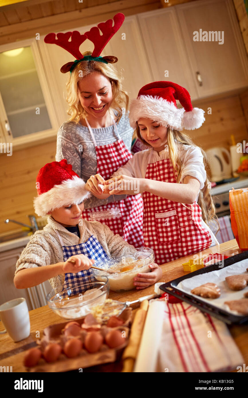 smiling children and mother baking Christmas cookies at home on Xmas ...