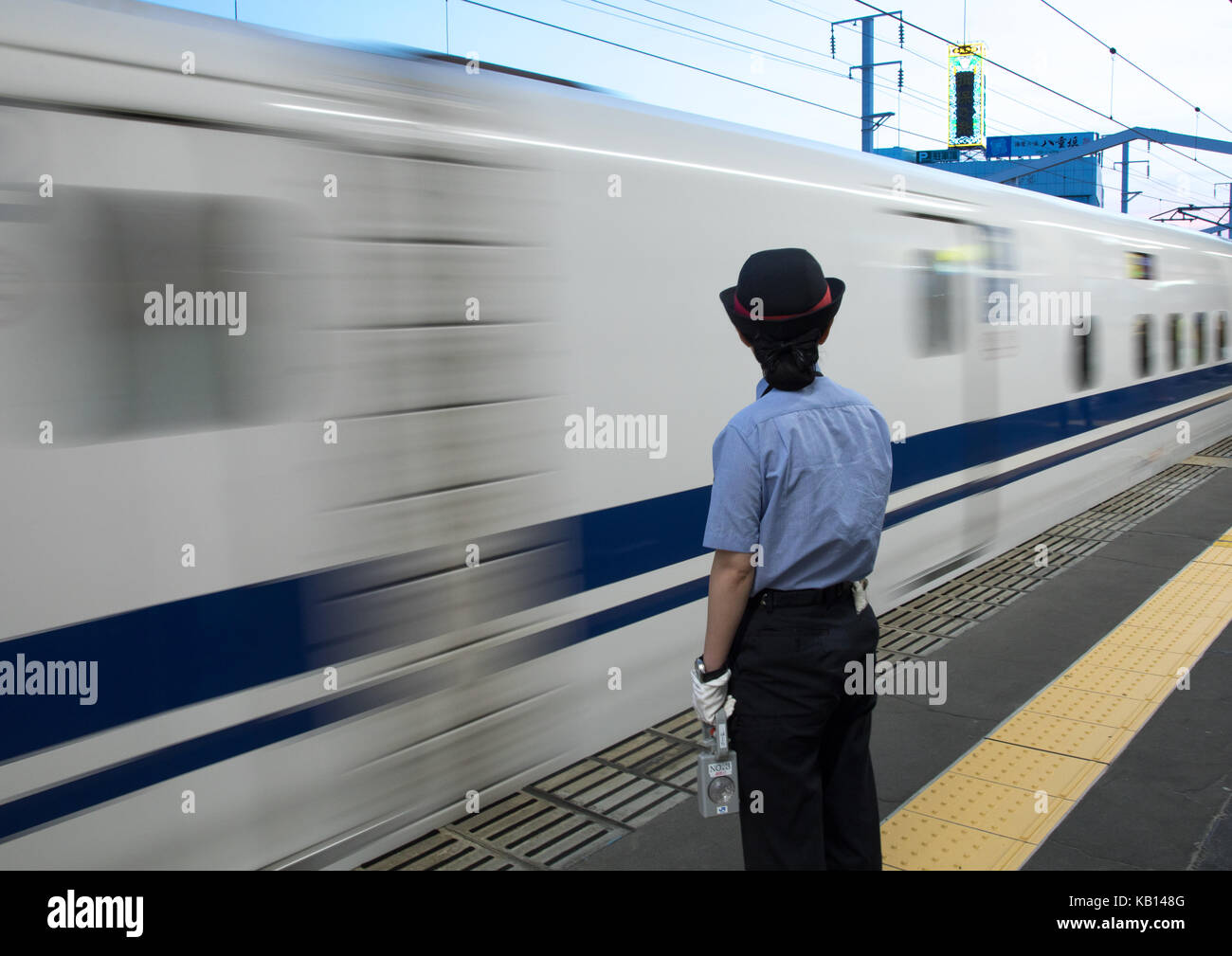 Japanese female station master in front of a shinkansen train in a ...