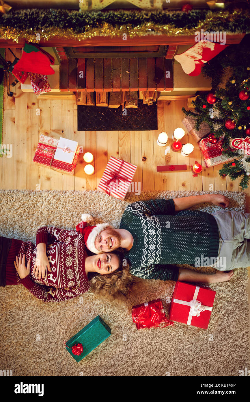 Man and woman laying down on the carpet near Christmas gifts Stock ...