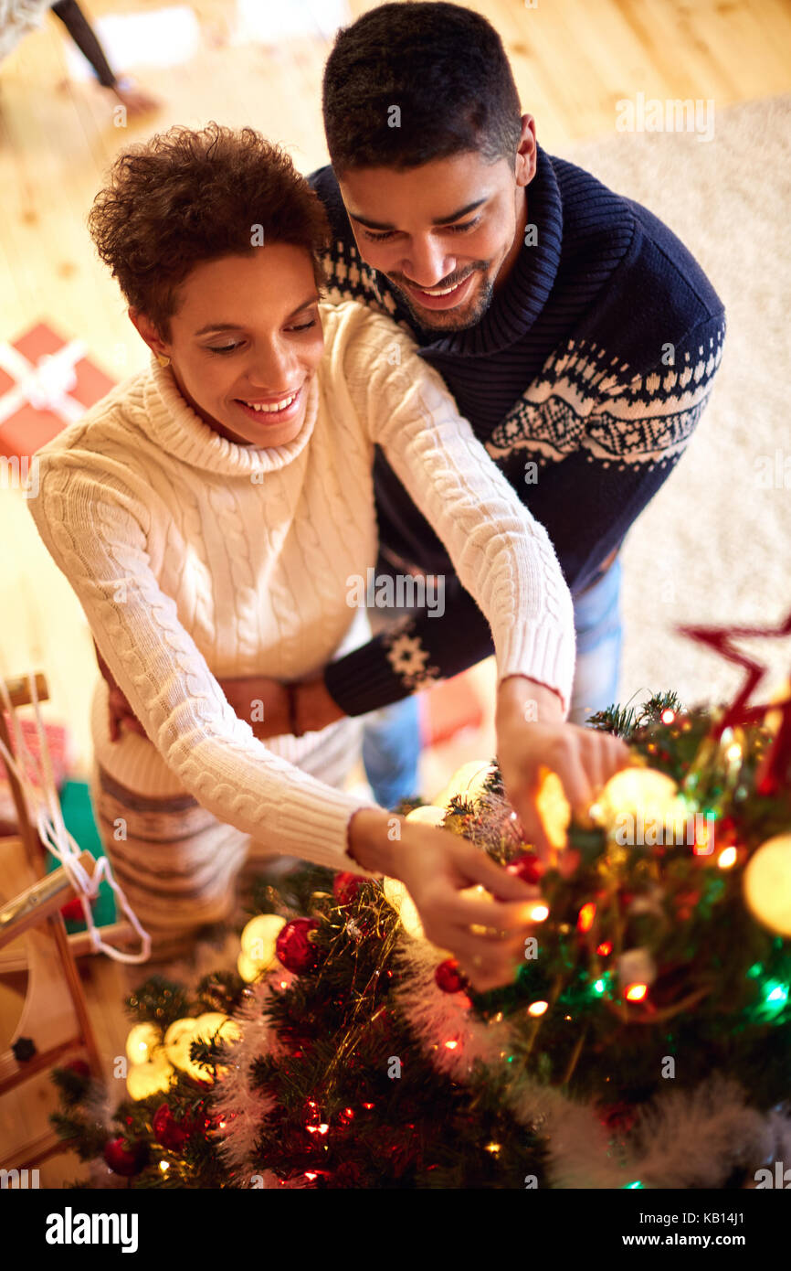 Smiling young couple decorated Christmas tree Stock Photo - Alamy