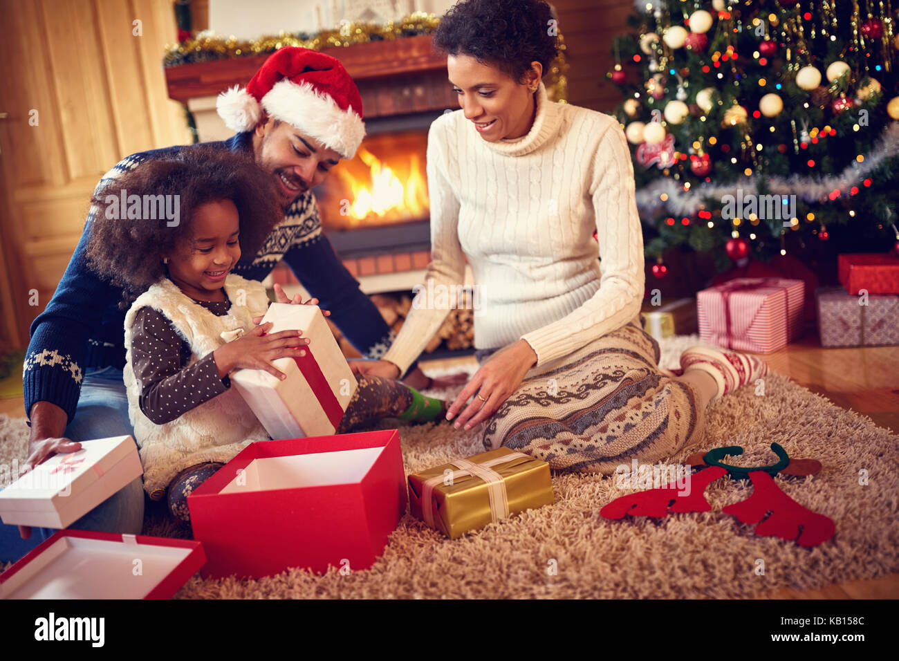 Happy family in Christmas morning opening present in home front of ...