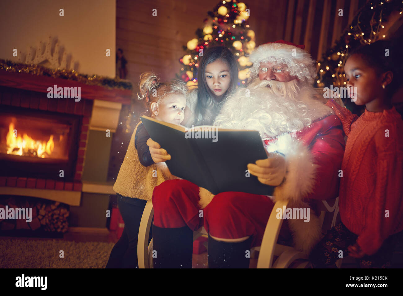 Santa Claus with three multi ethnic girls reading magic Christmas fairy ...