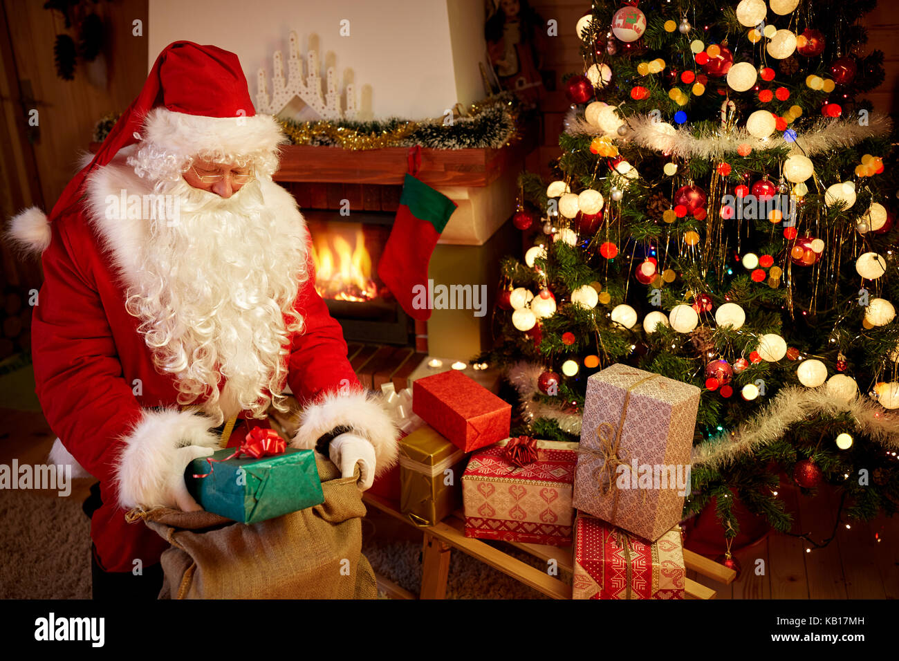 Santa Claus standing in wooden home interior with gift boxes Stock ...