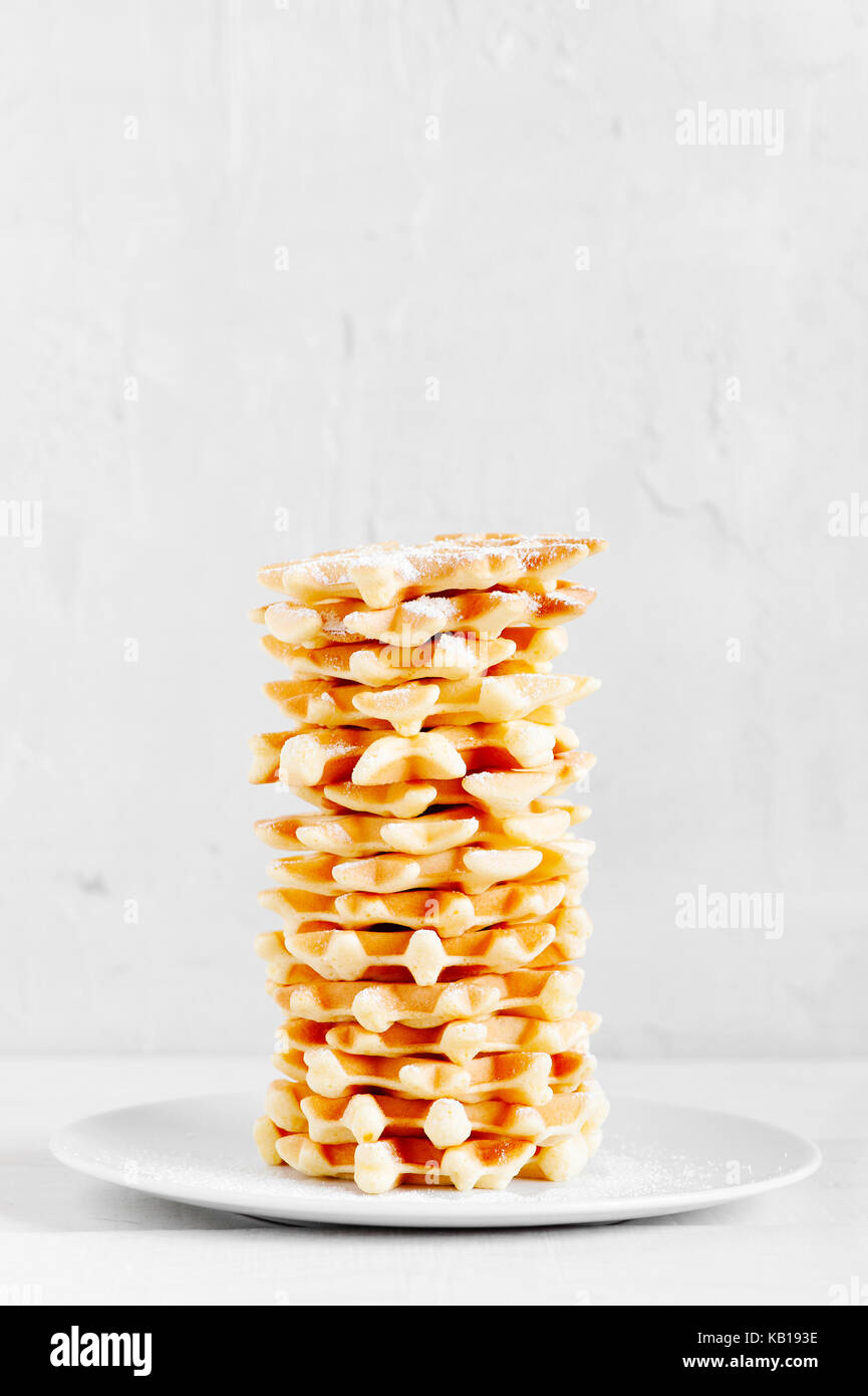 Stack of fresh waffles on the white plate, wooden table and wall Stock ...