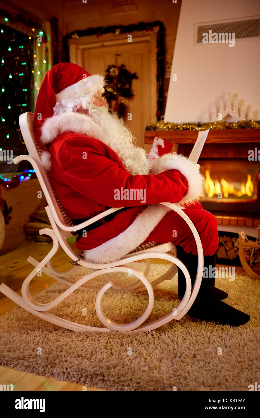Santa Claus relaxing at home sitting in rocking chair near Christmas ...