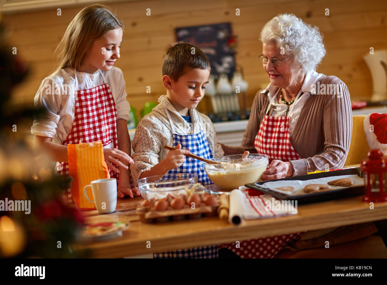 grandmother enjoying with children making Christmas cookies at home ...