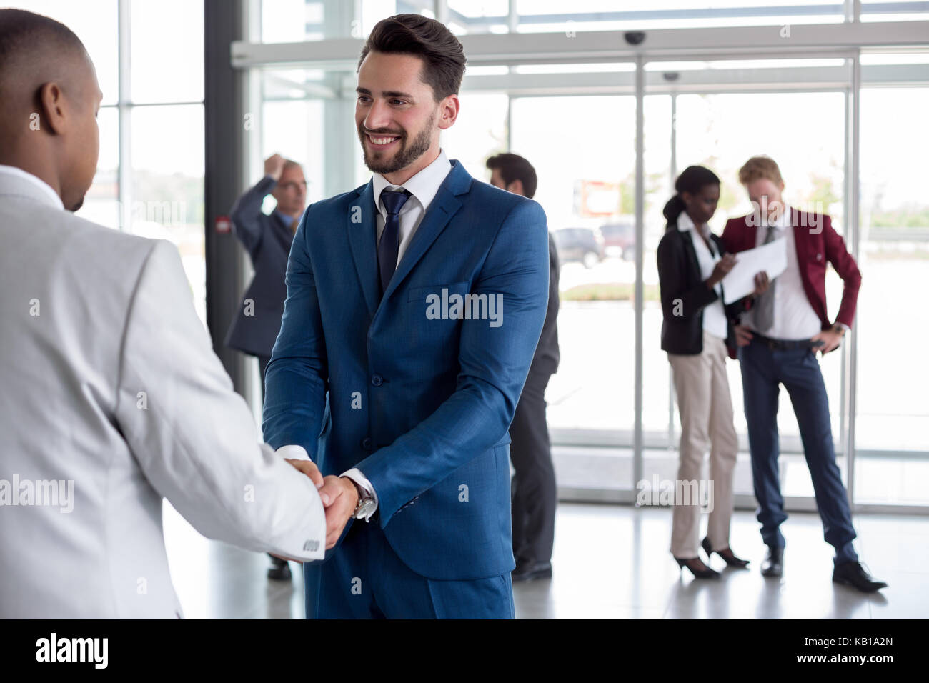 Handsome man at entrance heartily welcome black man Stock Photo - Alamy