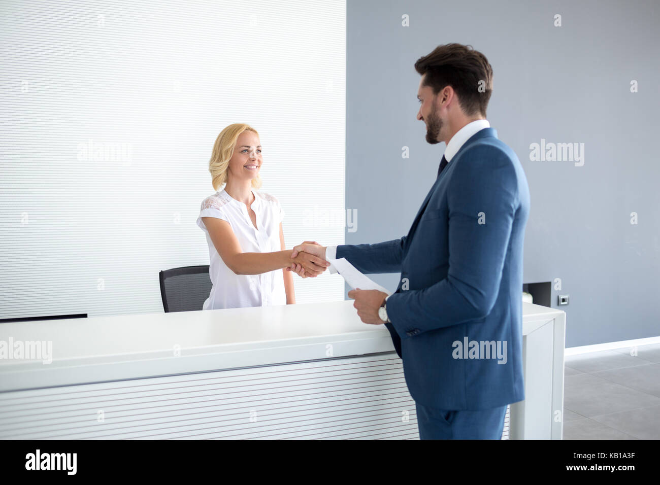 Kind female receptionist wish welcome to guest Stock Photo - Alamy