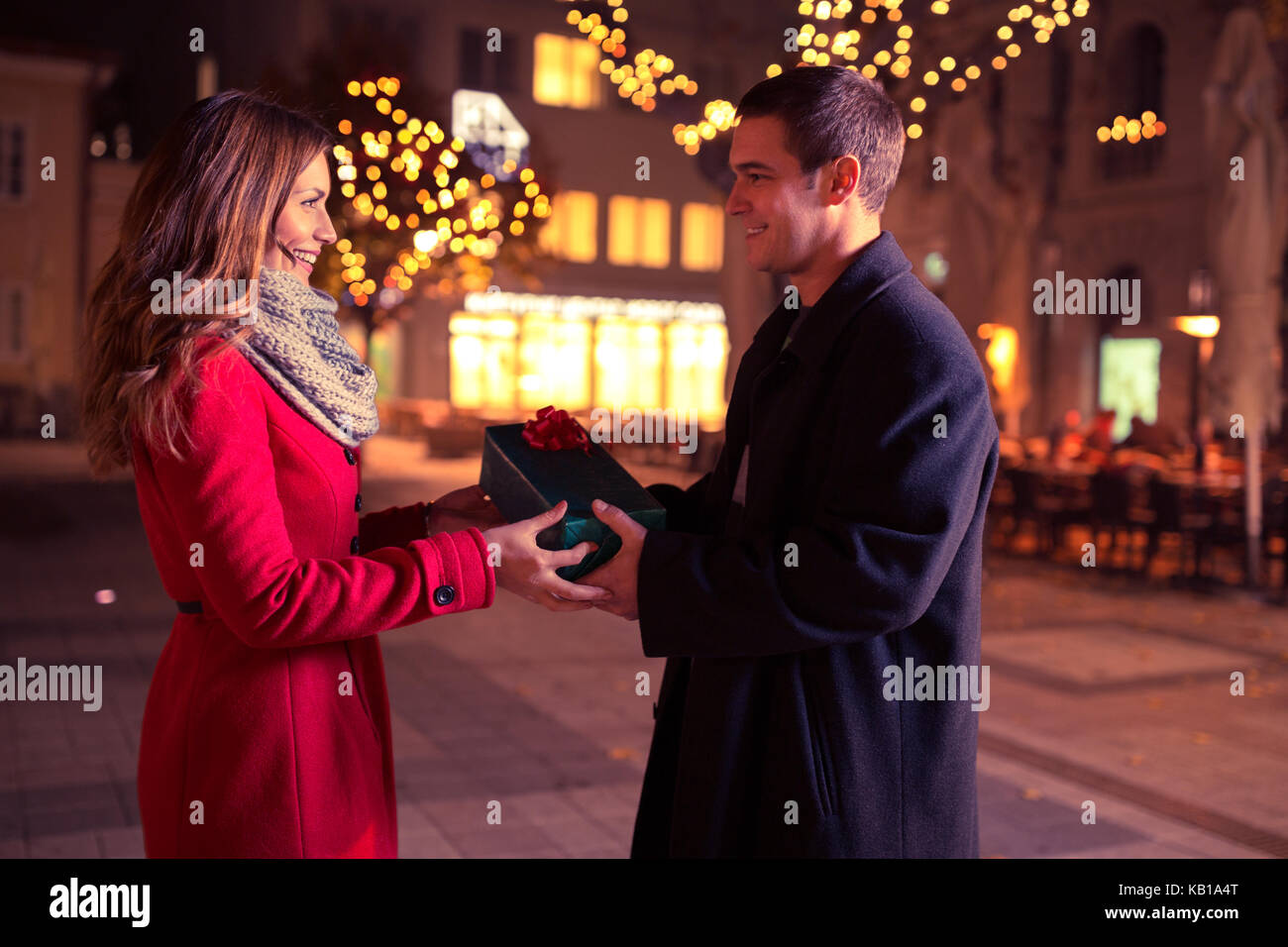 couple holding present looking at each other, young woman receives a ...
