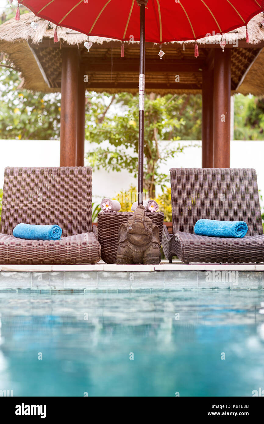Beach chairs near swimming pool in tropical resort Stock Photo - Alamy