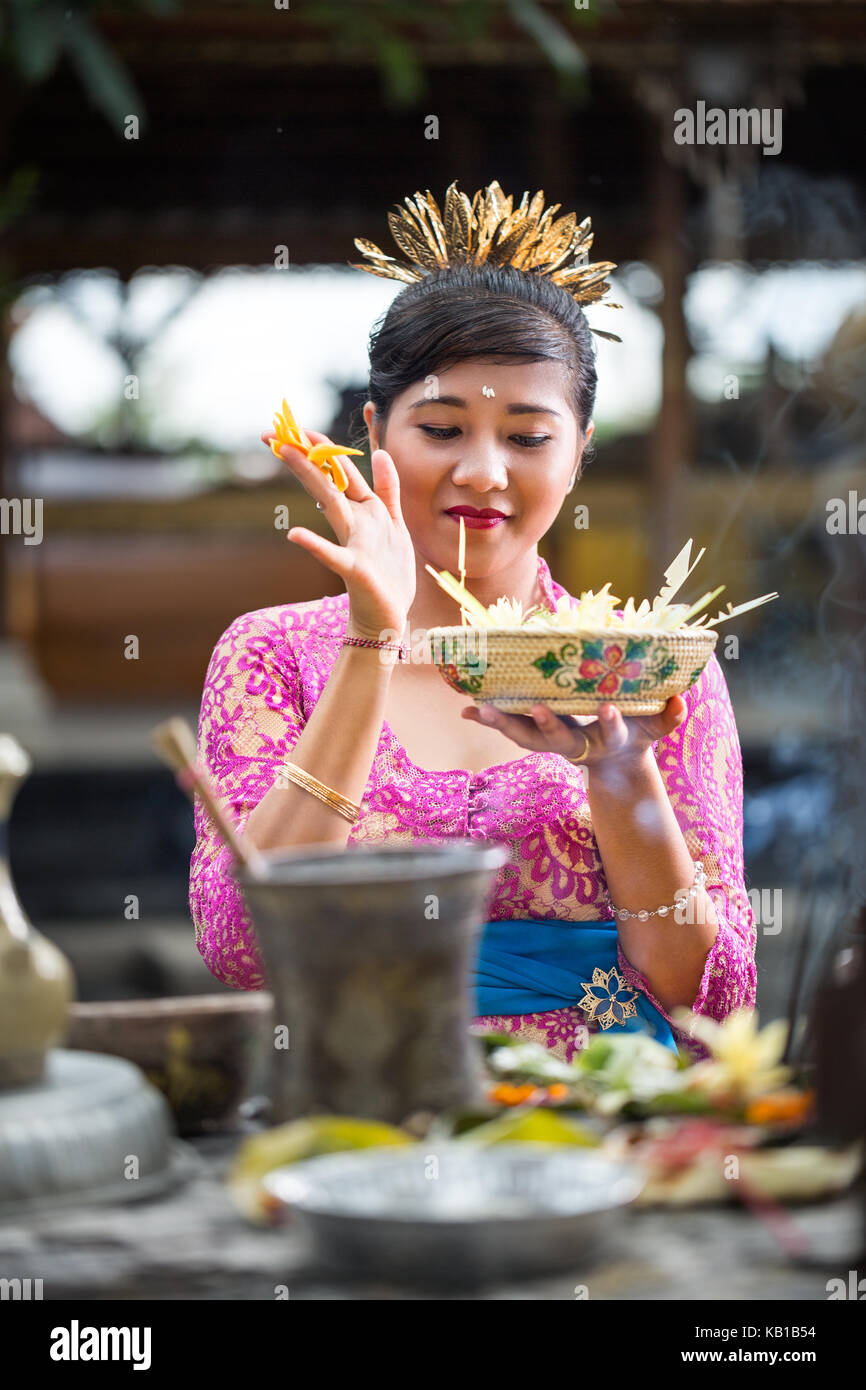 woman holding offering for gods and praying in Bali temple Stock Photo ...