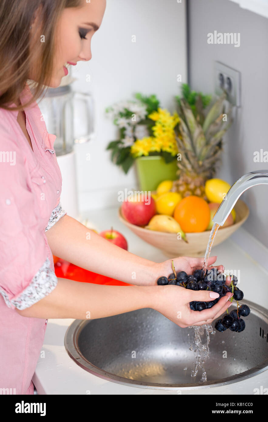 Woman washing fresh grapes in the kitchen sink Stock Photo - Alamy